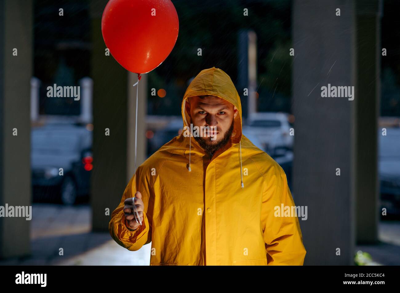 Scary man with balloon walking in night park Stock Photo - Alamy