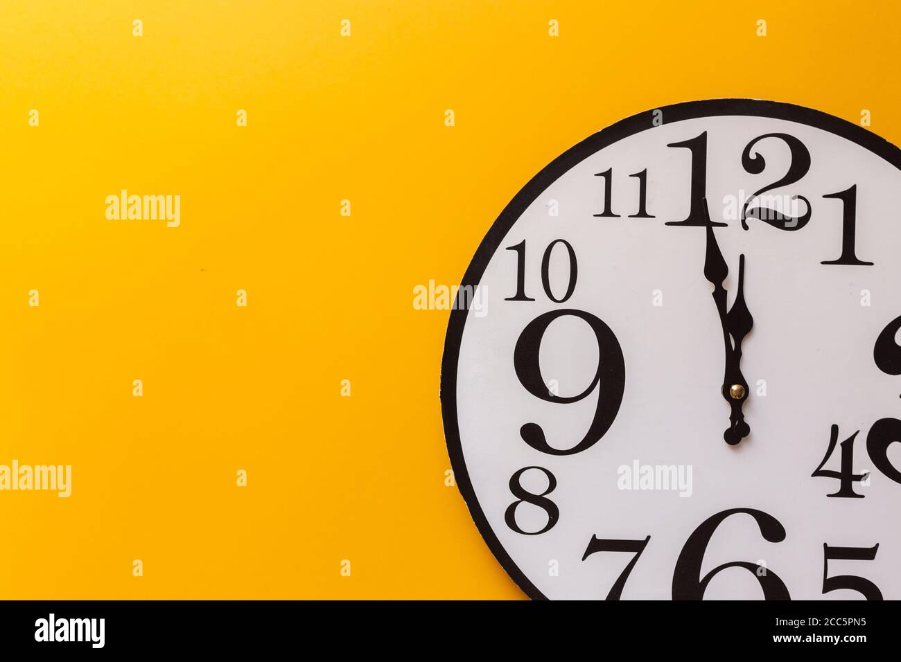 Black and white clock showing one minute to midnight, isolated on ...