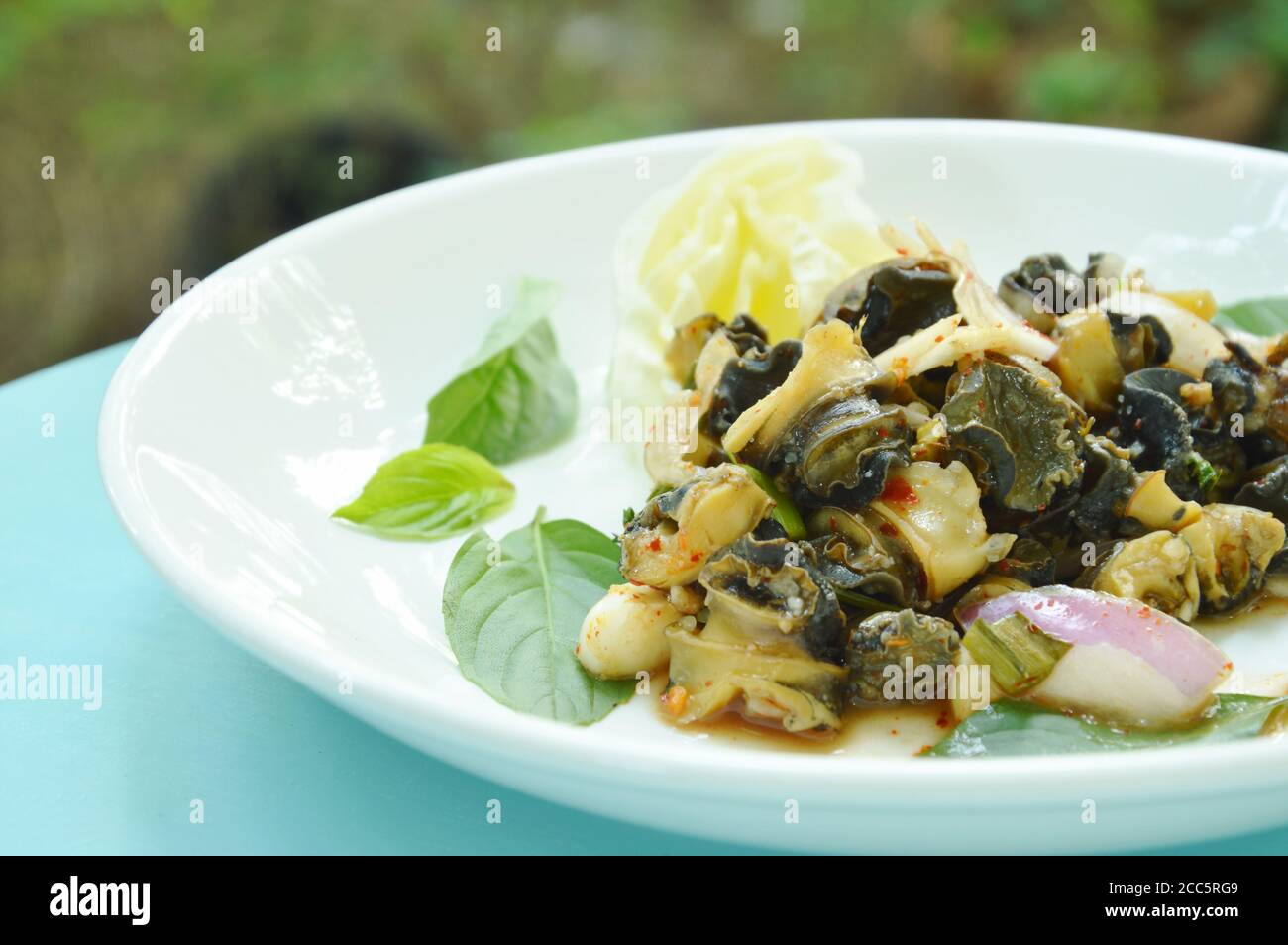 spicy golden apple snail with herb salad on white plate Stock Photo - Alamy