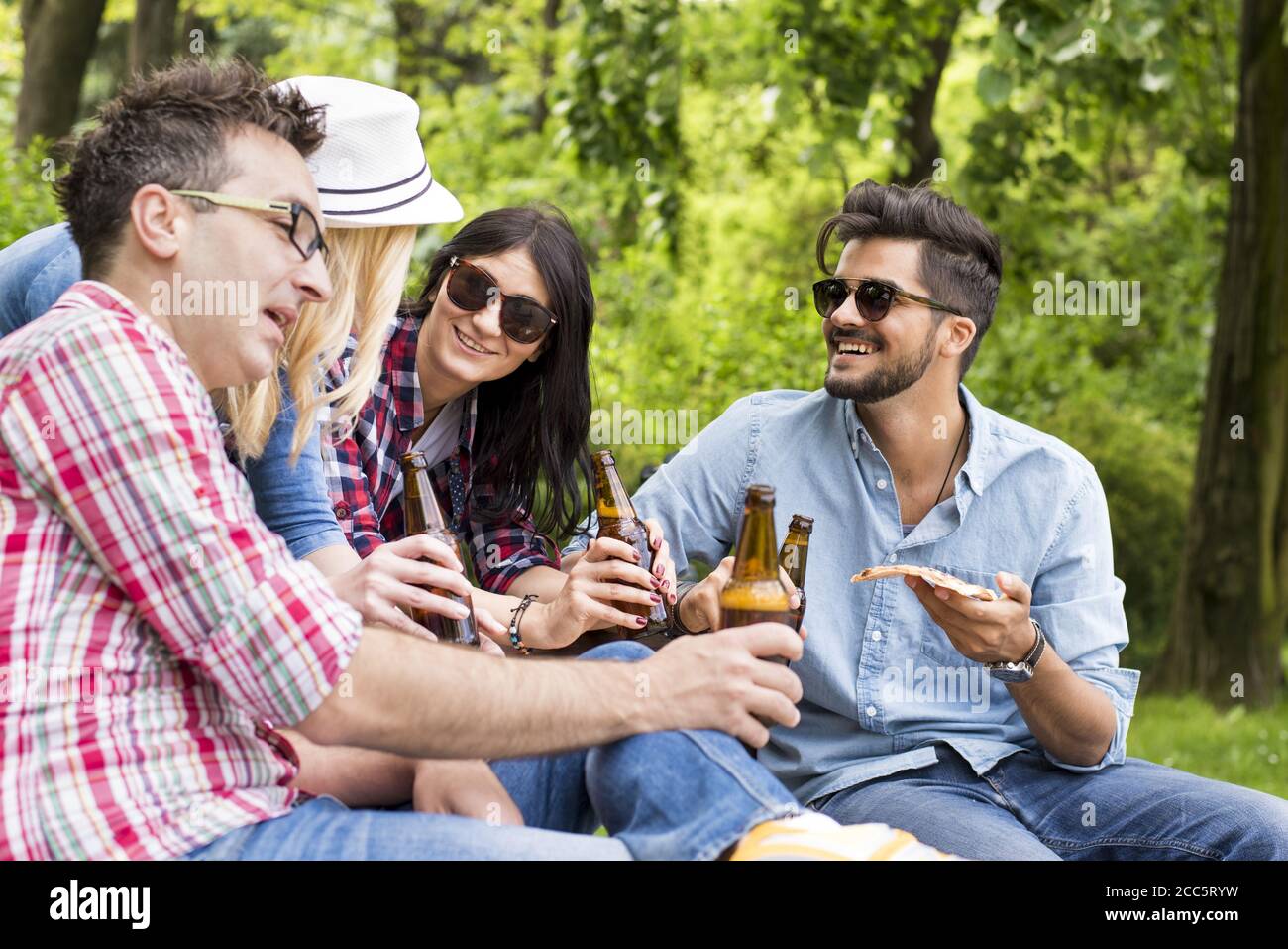 Group of caucasian friends sitting on the bench and enjoying their beer ...