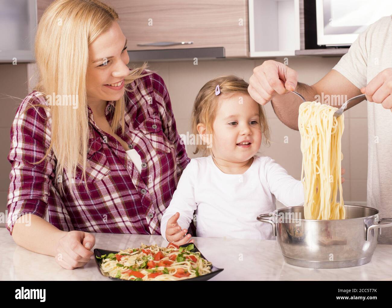 Happy family and their little daughter preparing homemade spaghetti on ...