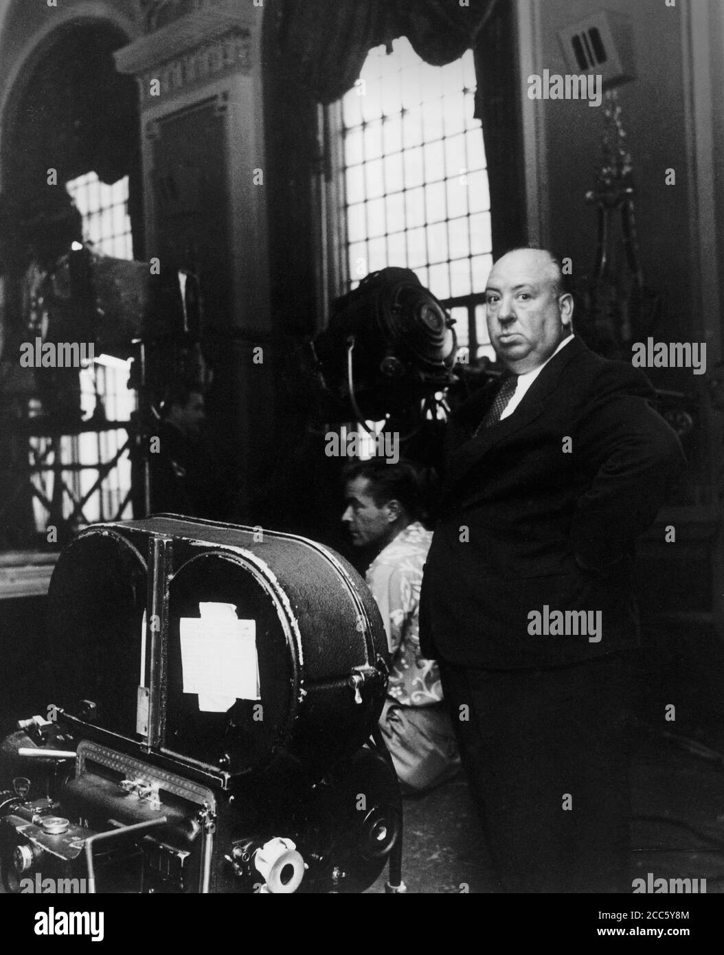 Film director Alfred Hitchcock standing next to a movie camera on the ...
