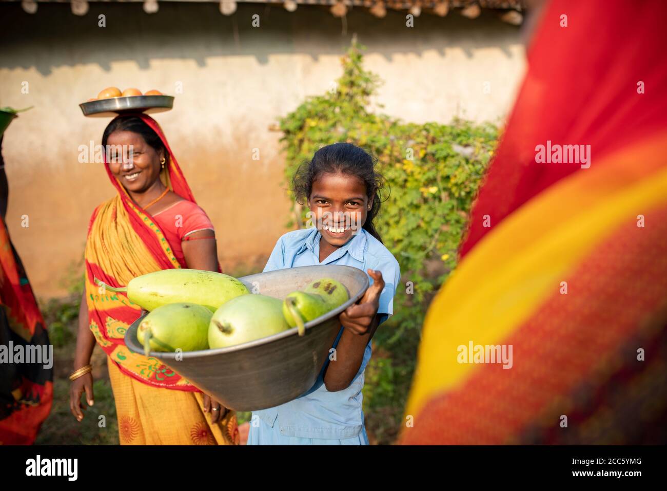 A woman and her daughter carry freshly harvested gourds and vegetables ...