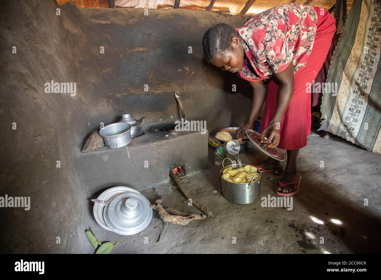 A South Sudanese refugee woman cooking on a fuel-efficient firewood ...