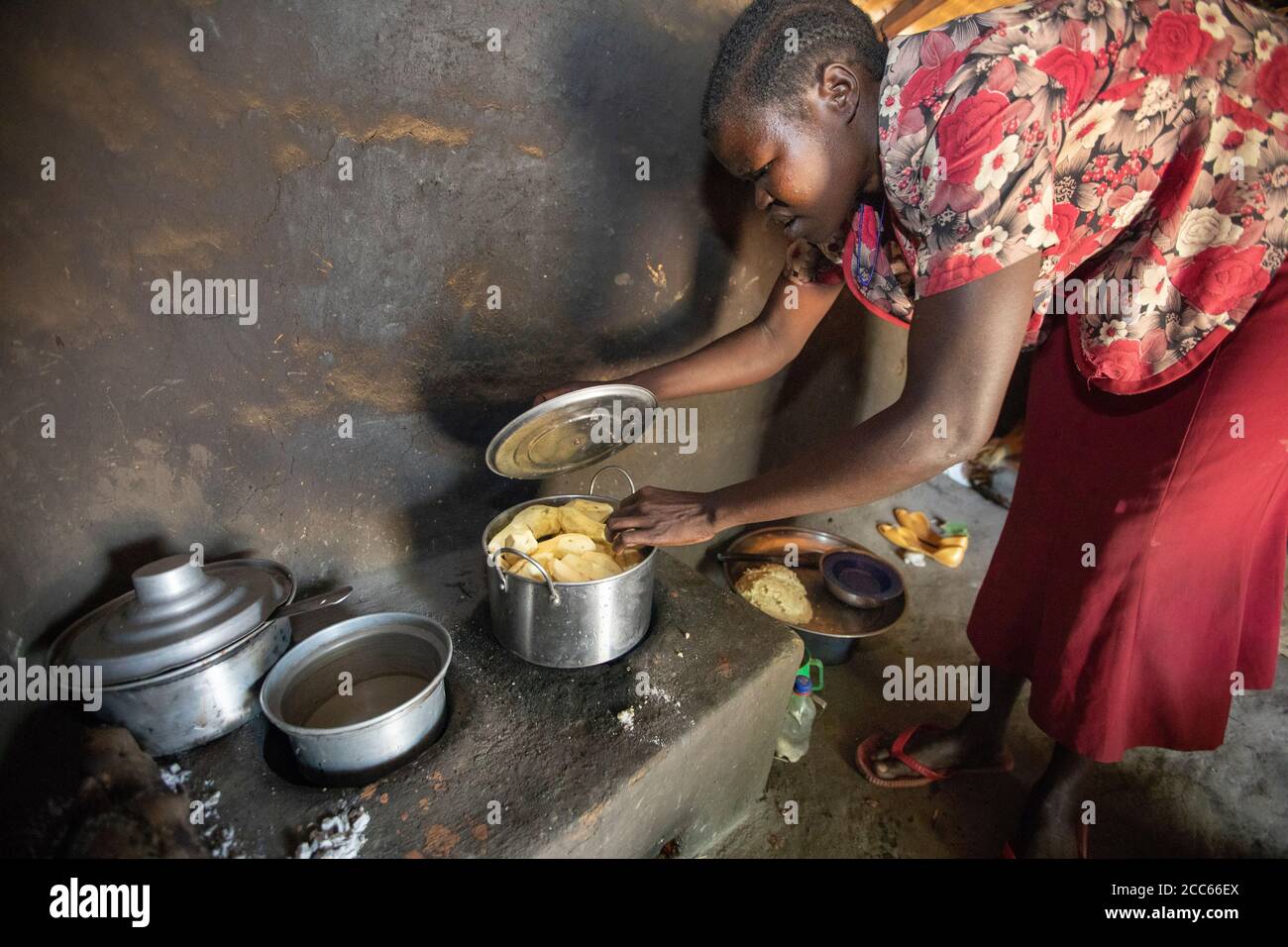 A South Sudanese refugee woman cooking on a fuel-efficient firewood ...