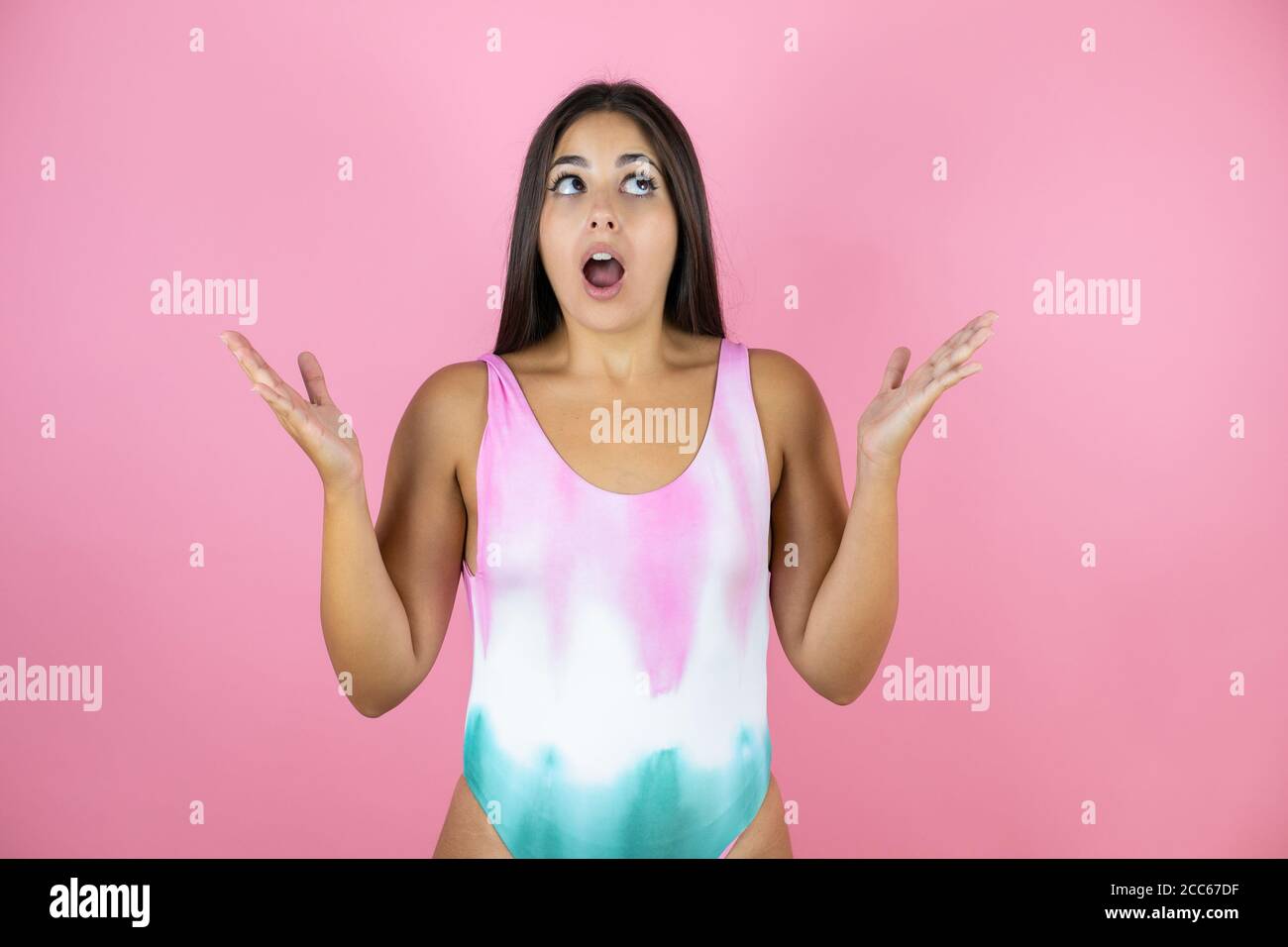 Young beautiful woman wearing swimsuit over isolated pink background ...
