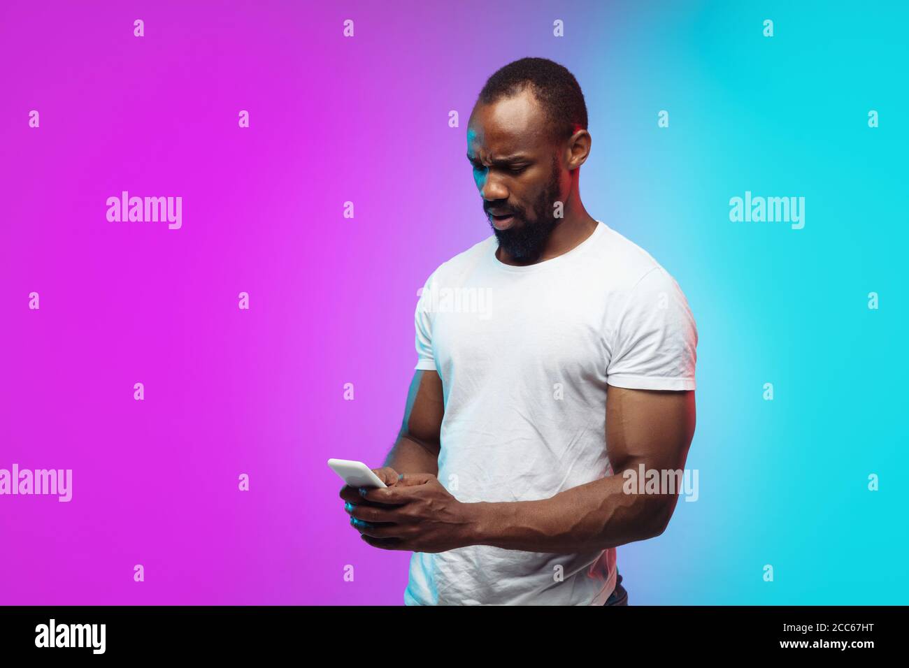 Scrolling phone. African-american young man's portrait on gradient ...