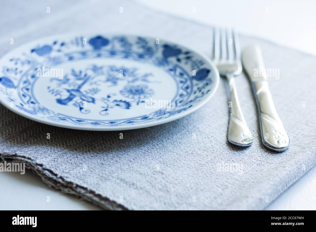 Table setting for dinner: a plate, a fork, a knife on a woven cloth ...