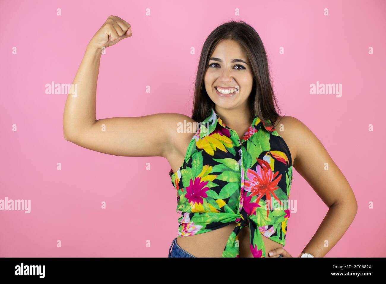 Young woman over isolated pink background showing arms muscles smiling ...