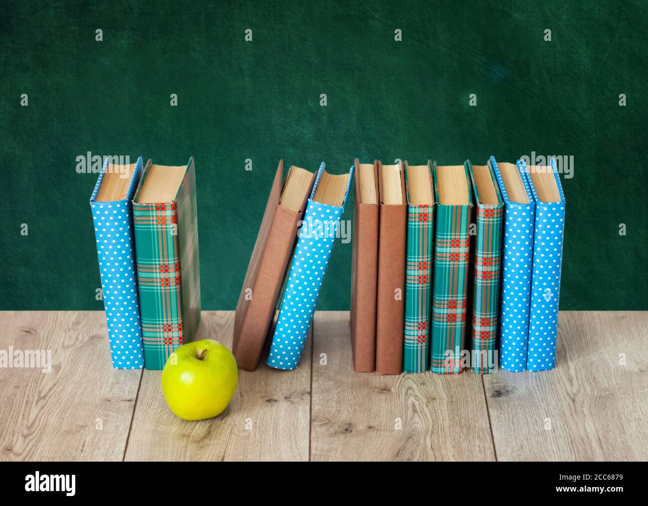 Back to school, pile of books in colorful covers and green apple on ...