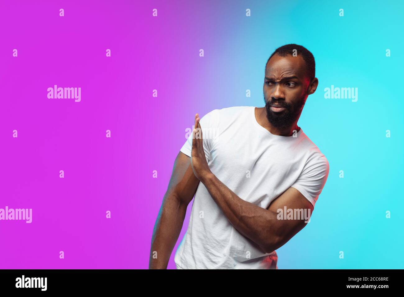 Avoiding. African-american young man's portrait on gradient studio ...