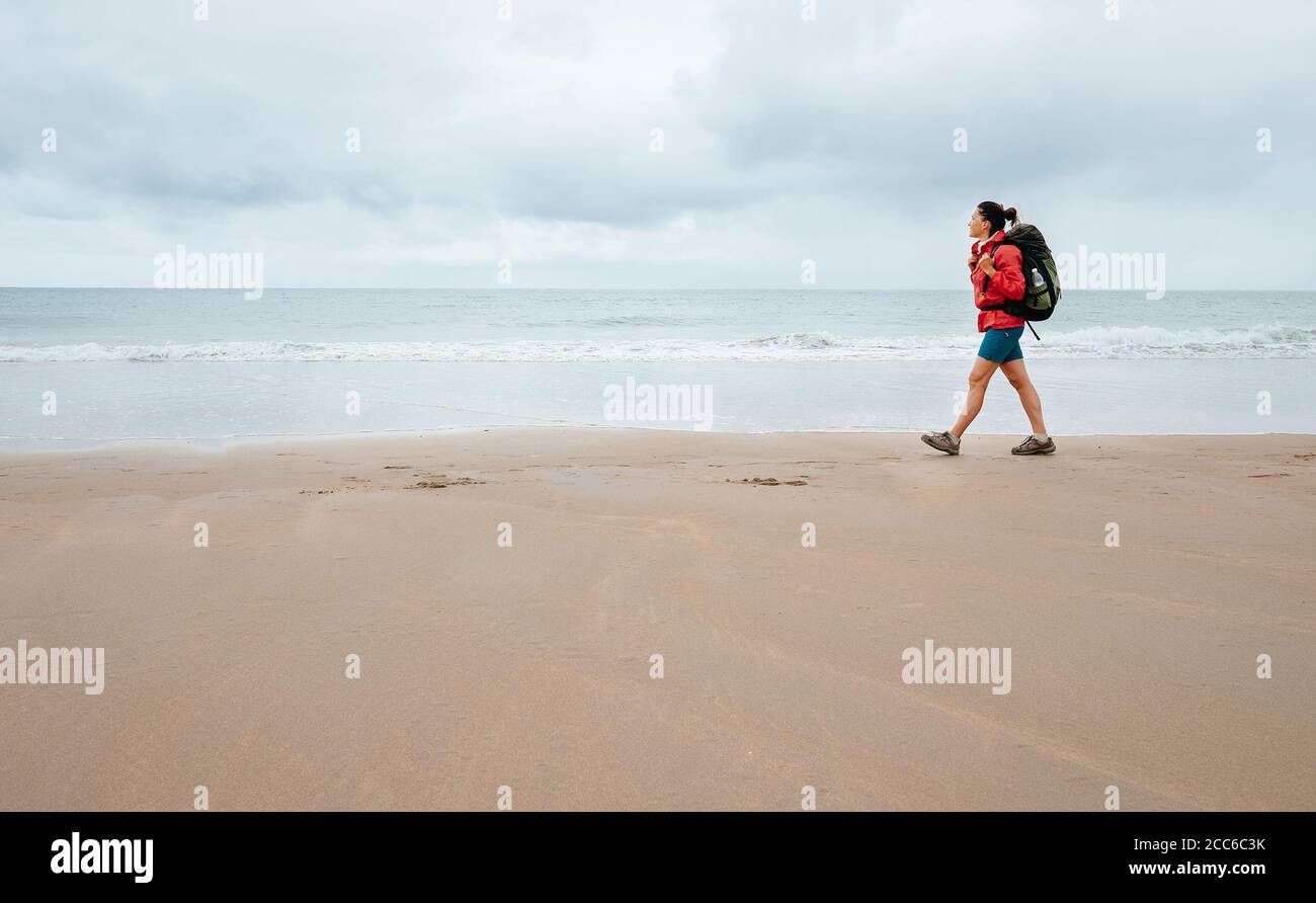 Woman traveler walk on empty ocean beach in rainy day Stock Photo - Alamy