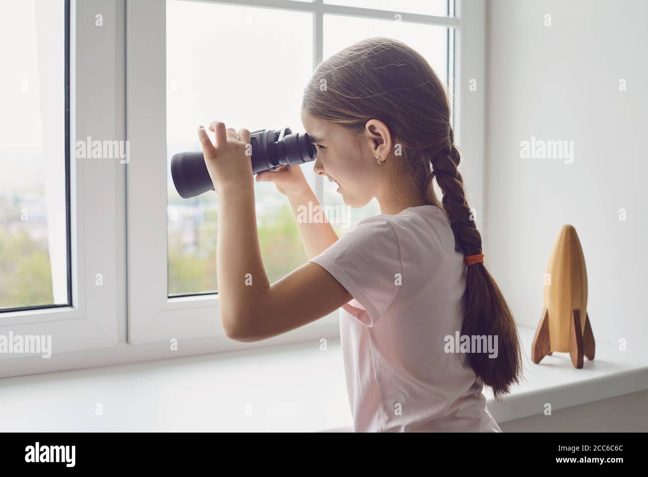 Home isolation concept during pandemic epidemic. A girl with binoculars ...