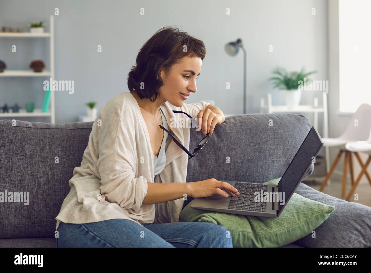 Young smiling woman communicating with somebody on laptop during online ...
