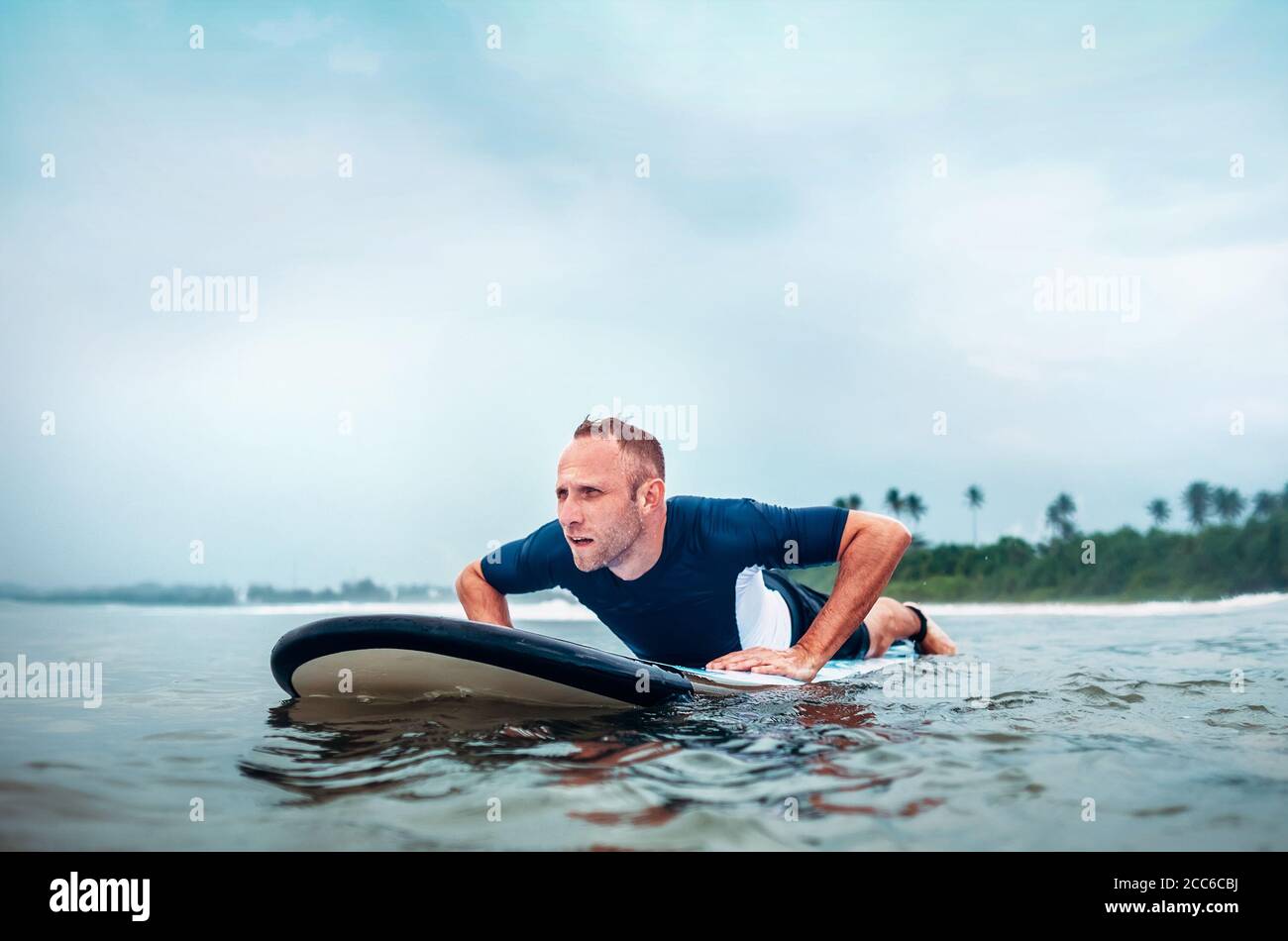 Surfer man floats on surf board, waits a waves Stock Photo - Alamy