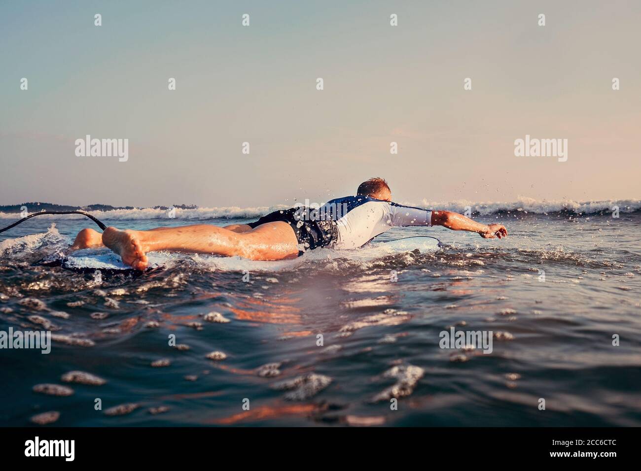 Man surfer swim on surfboard to waves line Stock Photo - Alamy