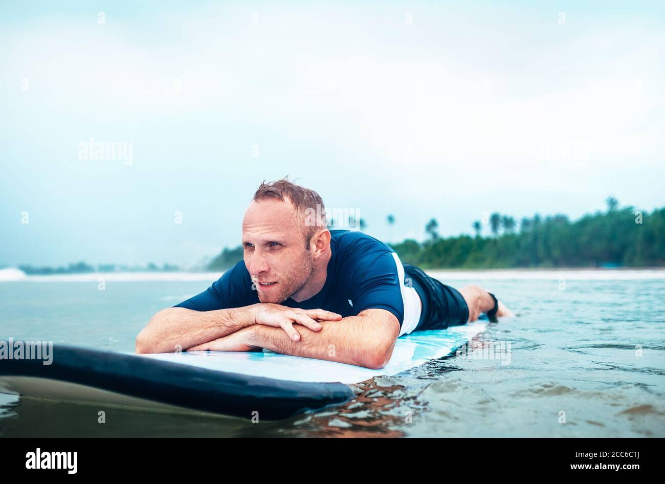 Man surfer rests lying on surfboard Stock Photo - Alamy
