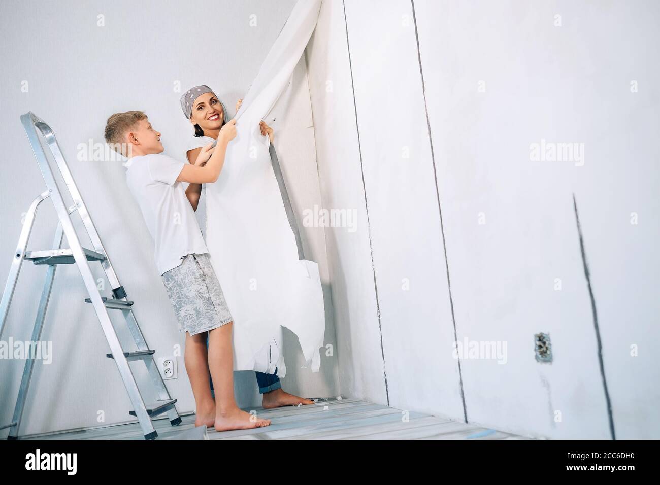 Mother and son take off wallpapers from wall and prepare room for ...