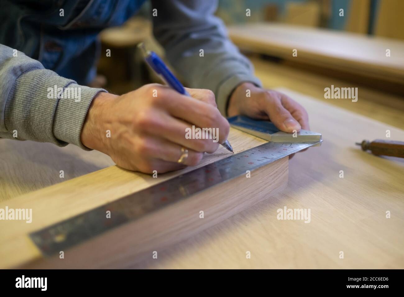 View of a carpenter using a pencil to draw a line on a wooden plank ...