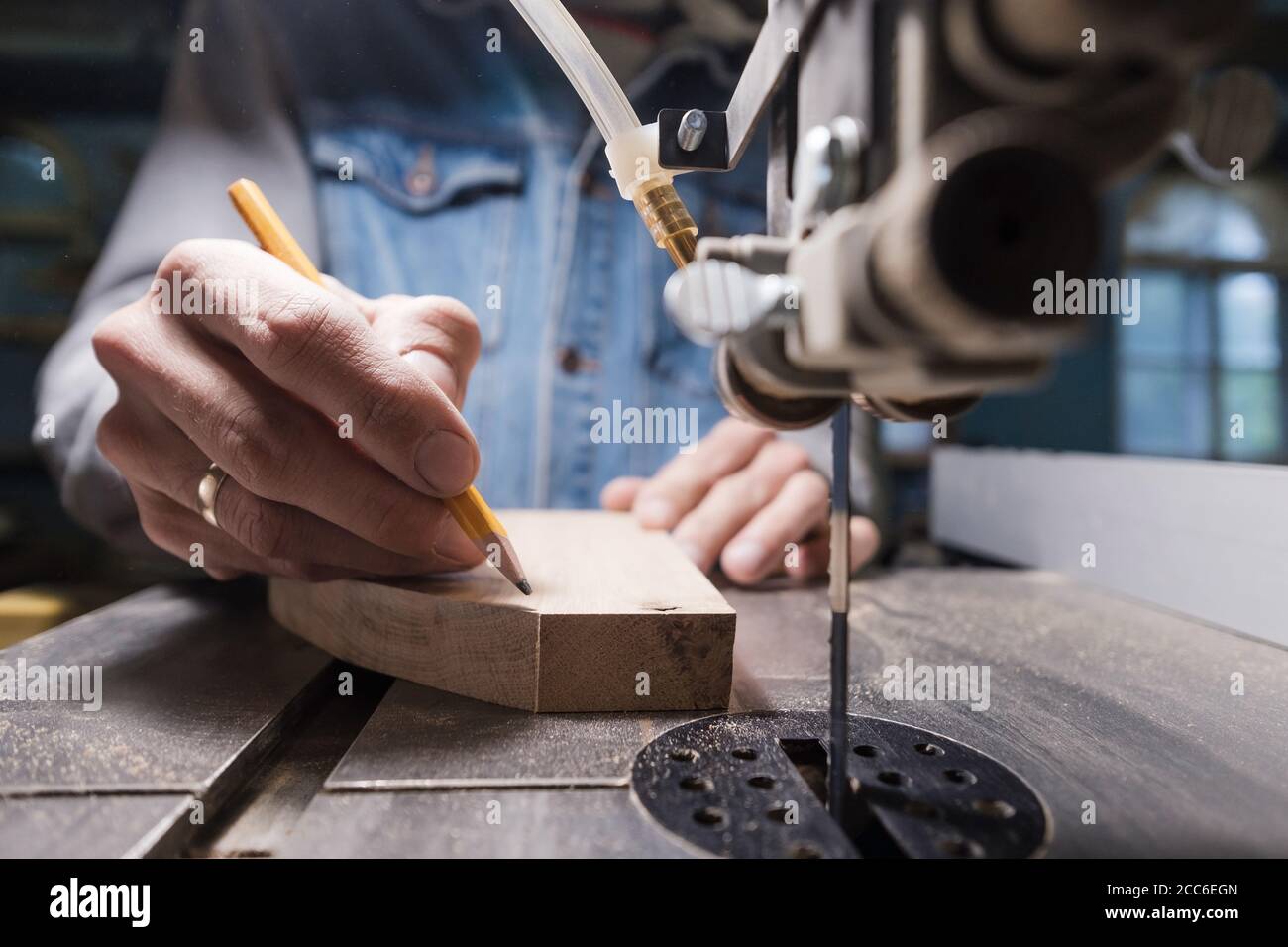 View of a carpenter using a pencil to draw a line on a wooden plank ...