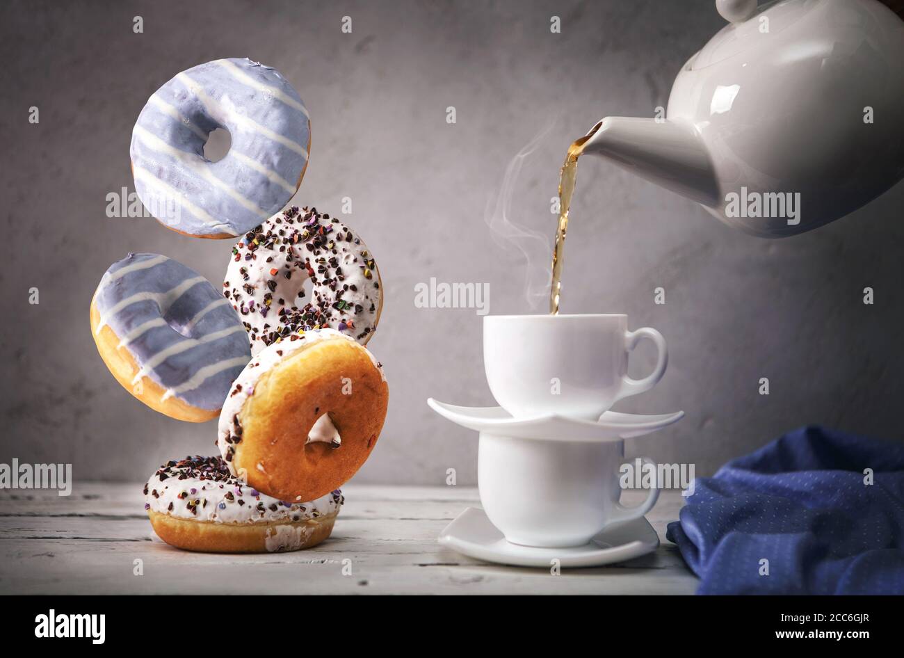Still life with tea and falling down donuts Stock Photo - Alamy