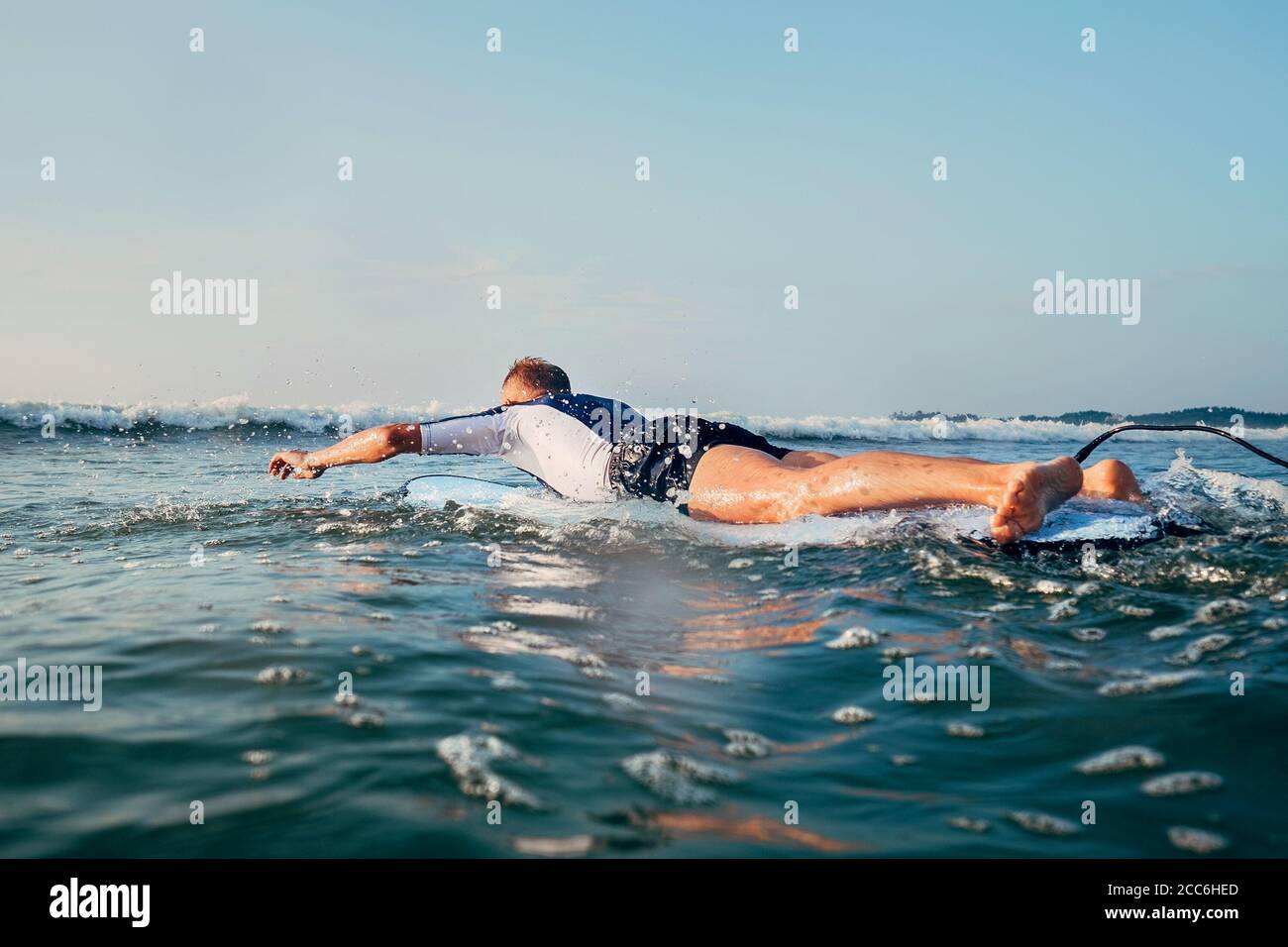 Man surfer swim on surfboard to waves line Stock Photo - Alamy