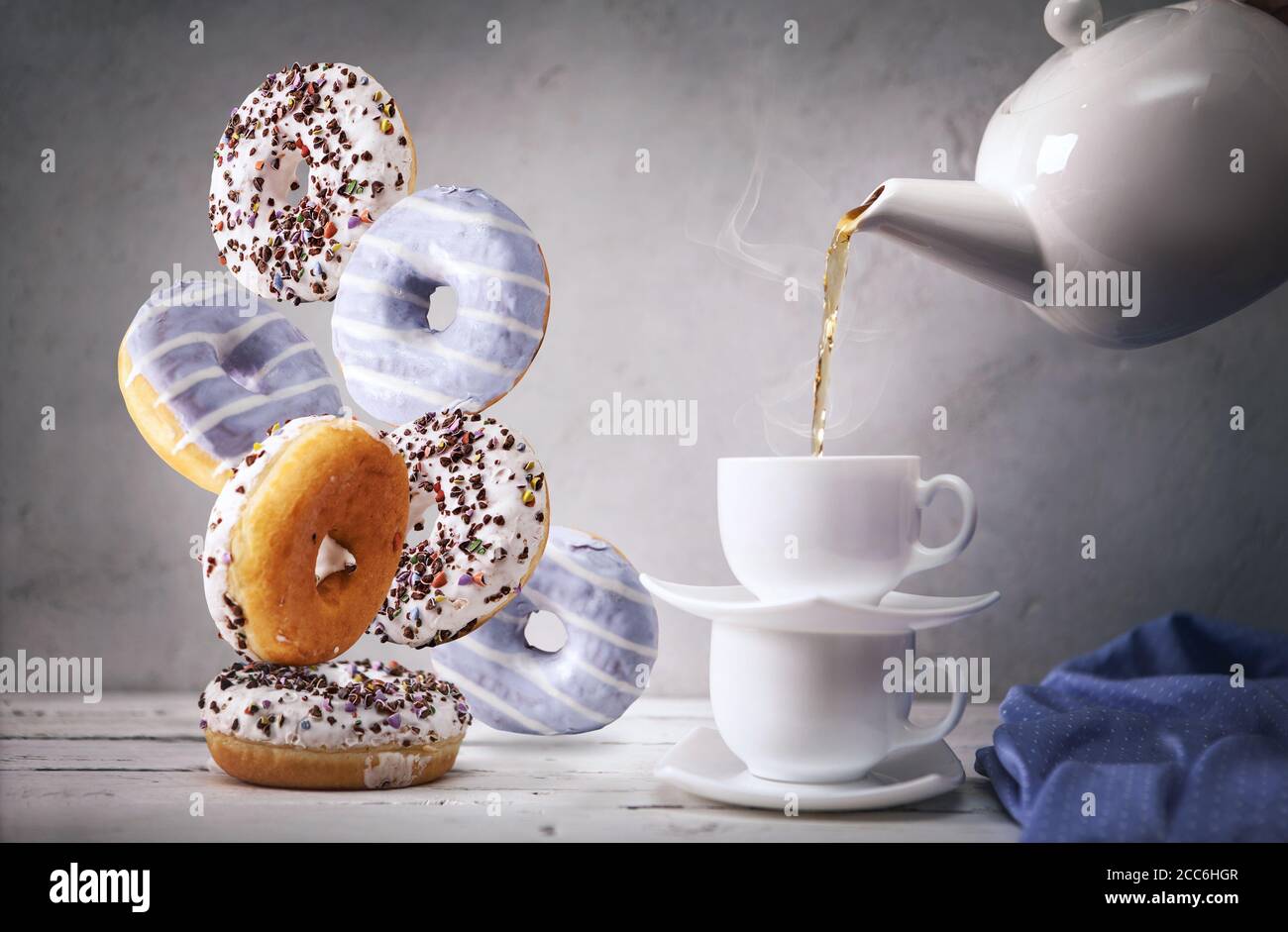 Still life with tea and falling down donuts Stock Photo - Alamy