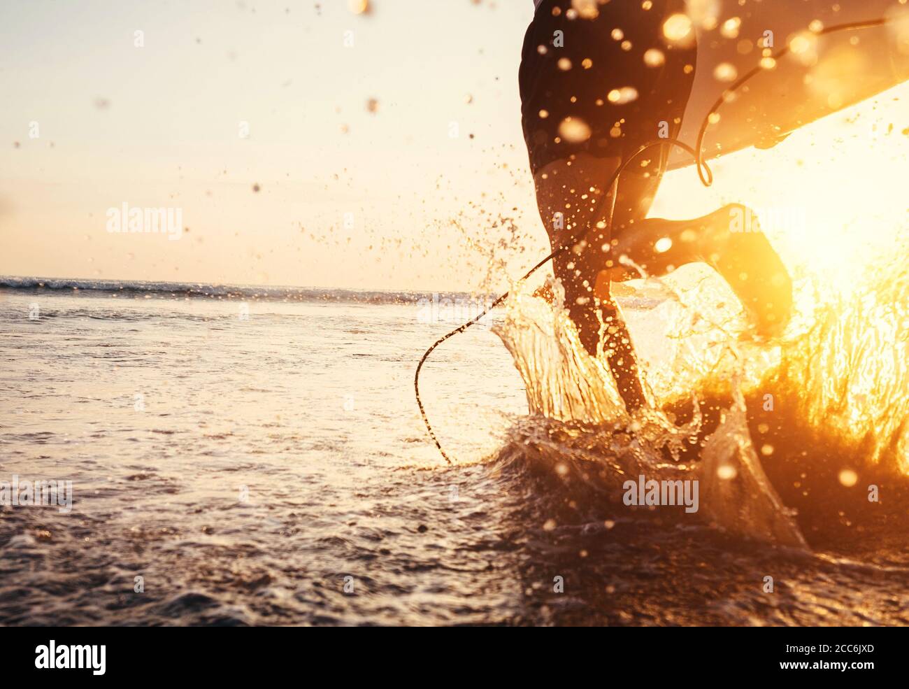 Man surfer run in ocean with surfboard. Closeup image water splashes ...