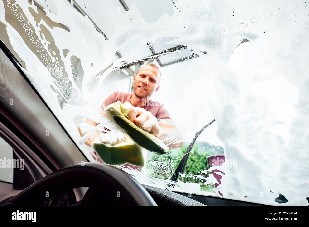 Car washing process: man washes front car window with soap Stock Photo ...