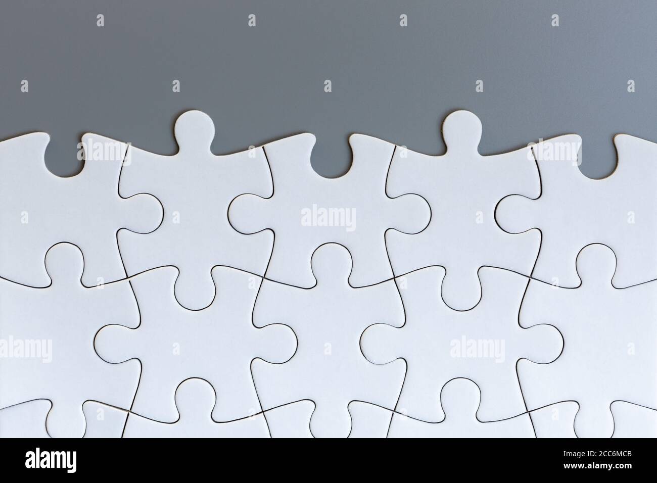 White jigsaw puzzle pieces on gray background Stock Photo - Alamy