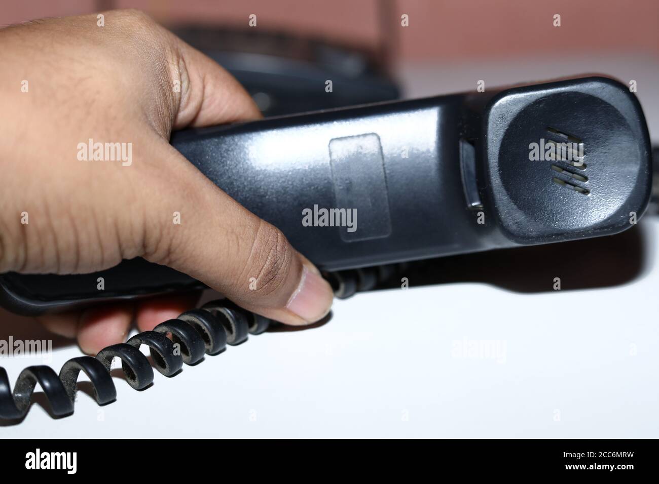 Male hand holding phone receiver on white backgrounds Stock Photo - Alamy