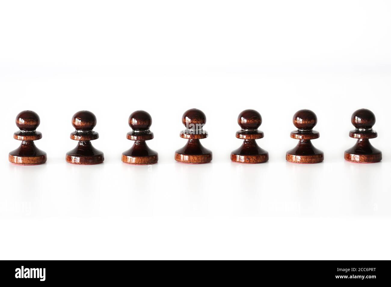 Row of seven black pawn chess pieces on white background Stock Photo ...