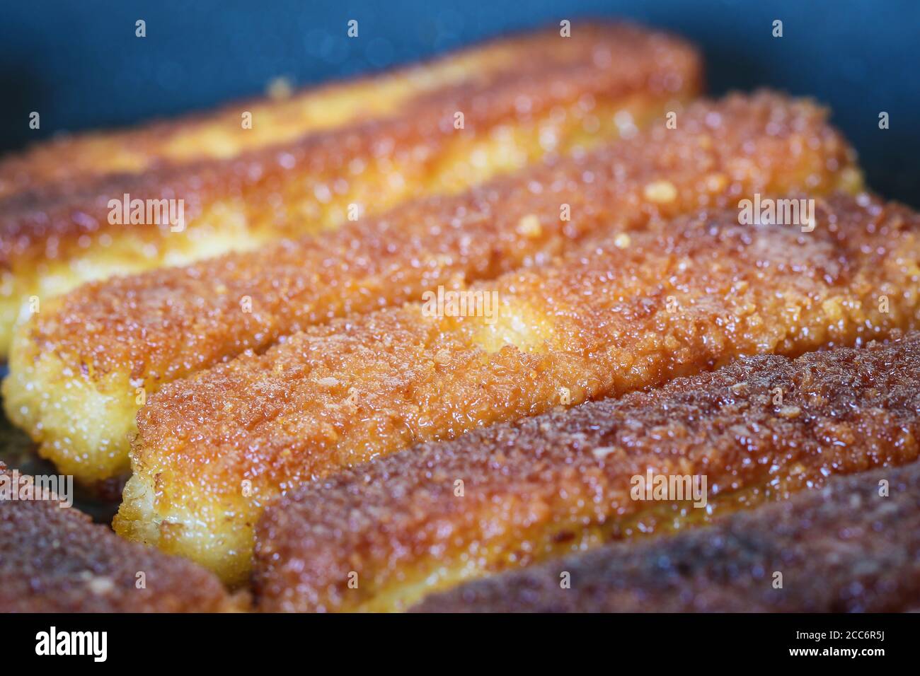 Fish fingers fry on frying pan with golden crunchy coating, closeup ...