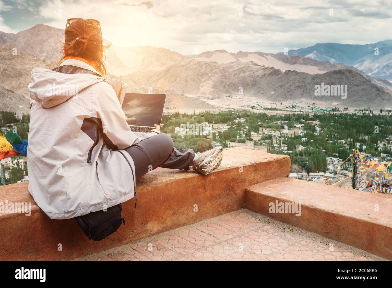 Traveler with laptop sits on top view point on the mountain valley ...
