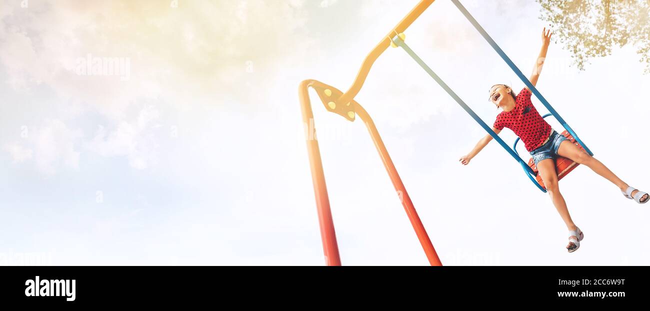 Happy smiling little girl swings on the high swing Stock Photo - Alamy