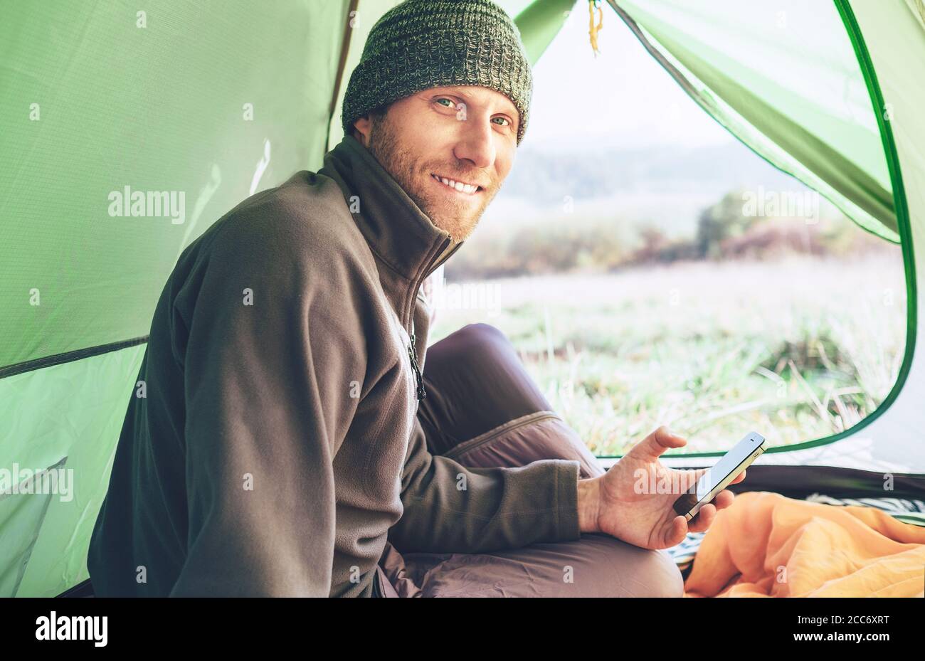 Bearded traveler warm dressed Man uses his mobile phone sitting in the ...