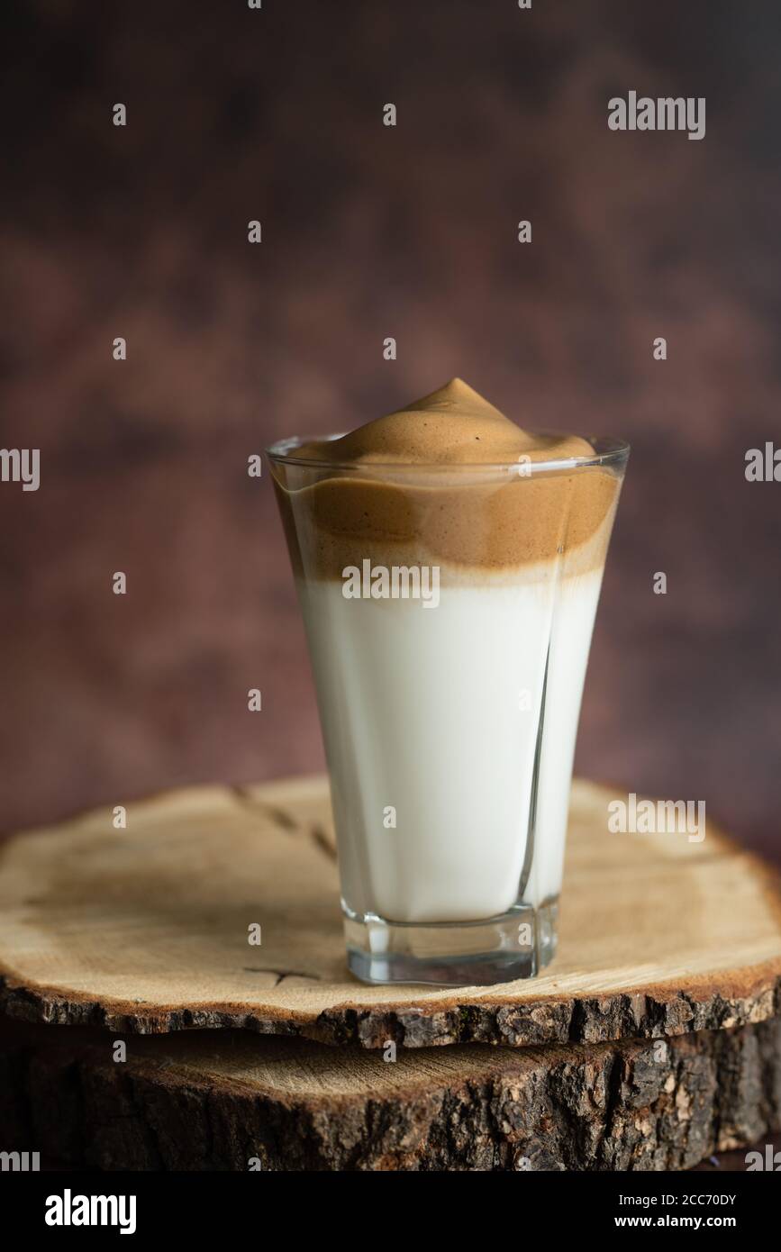 Dalgona cold coffee with milk and foam, on a cut wooden board, instant ...