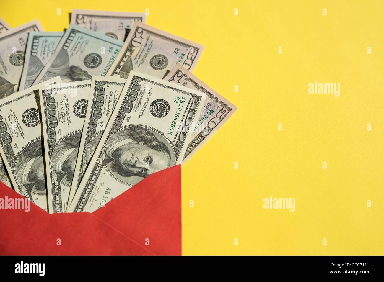 A stack of US dollar currency bills in an open red paper envelope. new ...