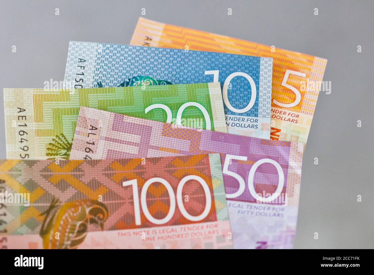 New Zealand cash, money or currency held fanned out on a gray ...
