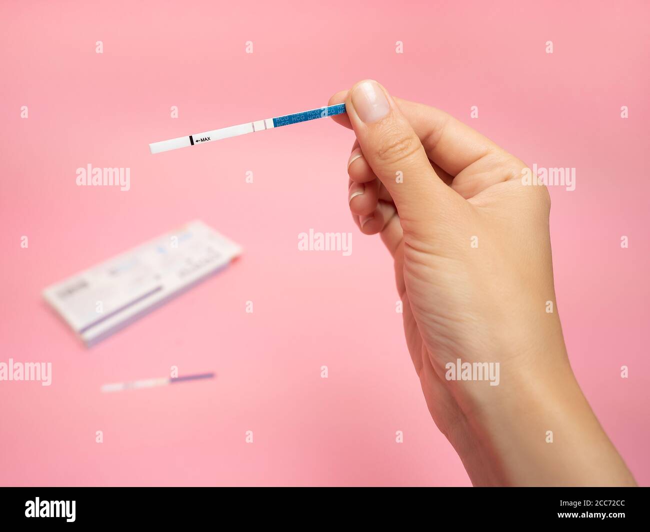 Female hand holding positive pregnancy test isolated on pink background ...