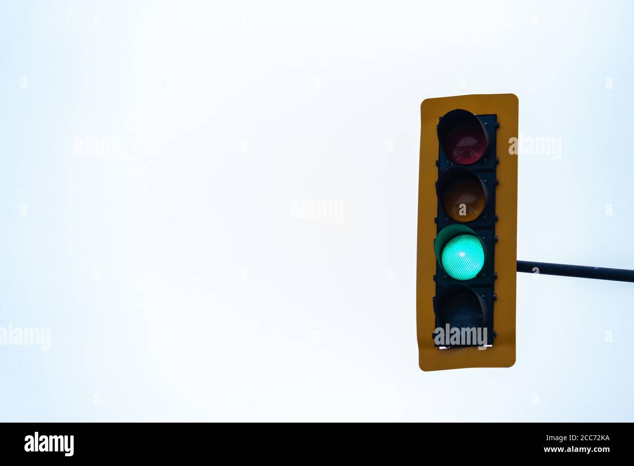 A traffic light signals green against a nearly solid white background ...