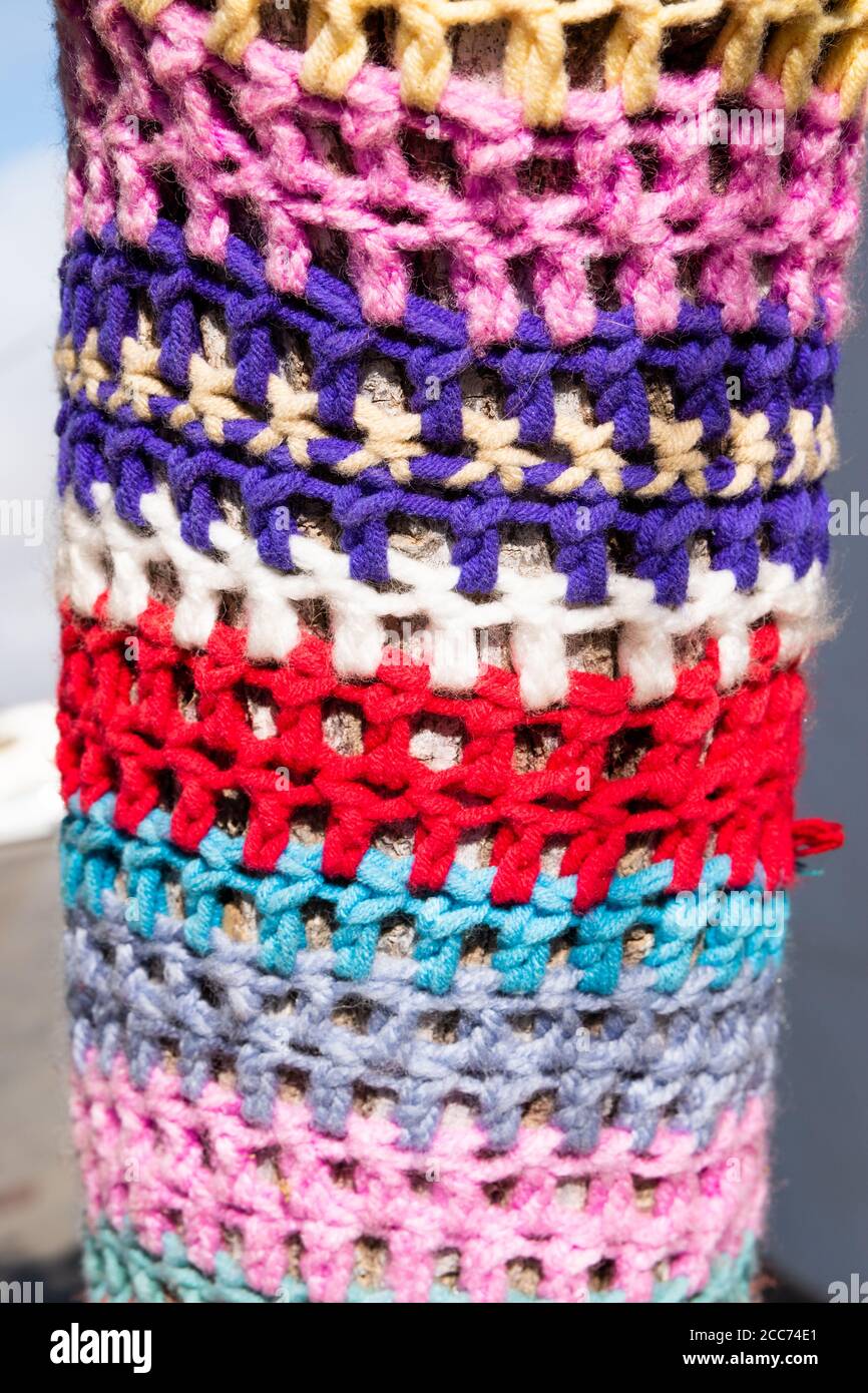 Tree trunk on the street covered with knitted and crocheted colorful ...