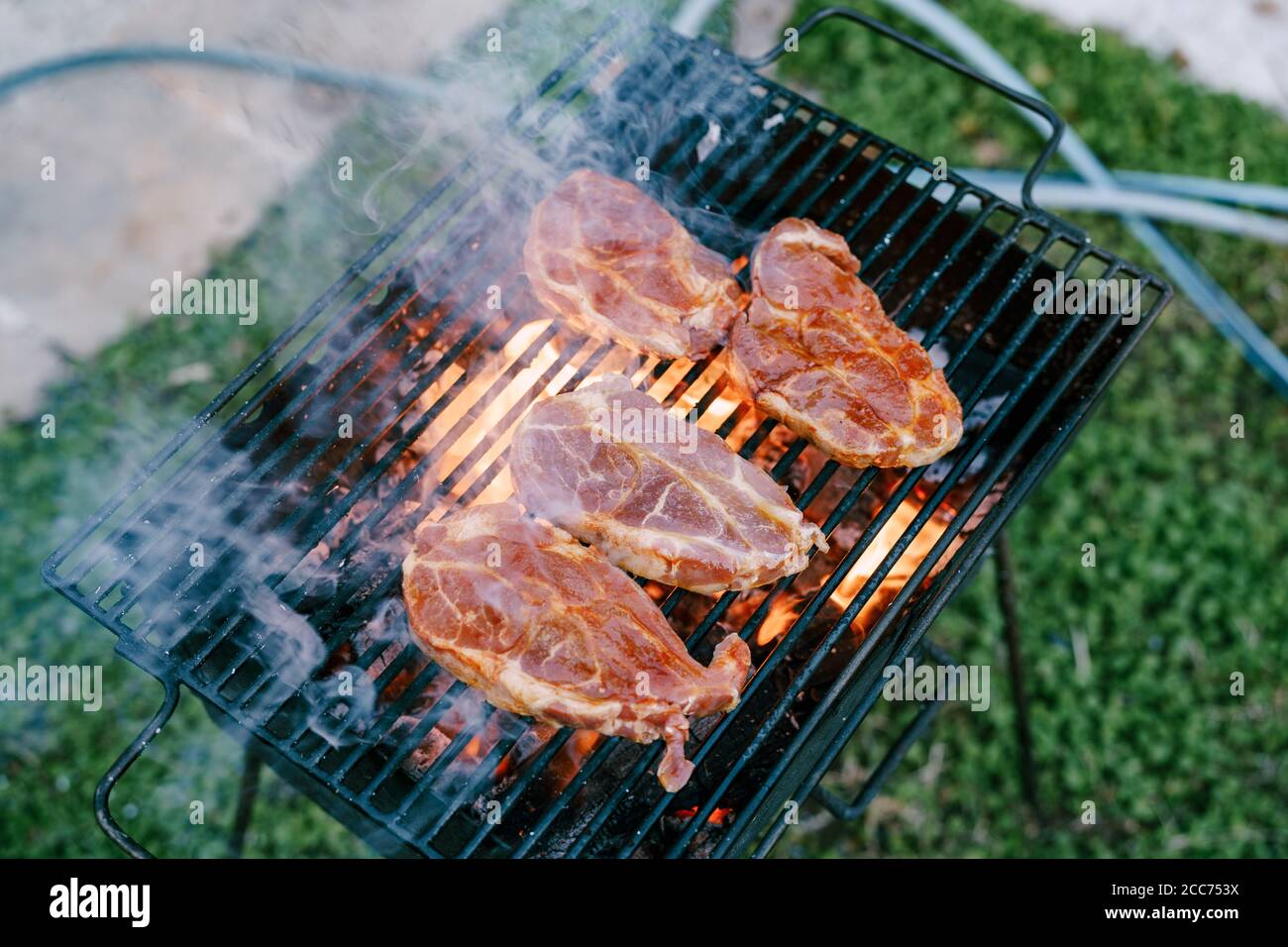 Raw steaks are grilled on an open fire with smoke Stock Photo - Alamy