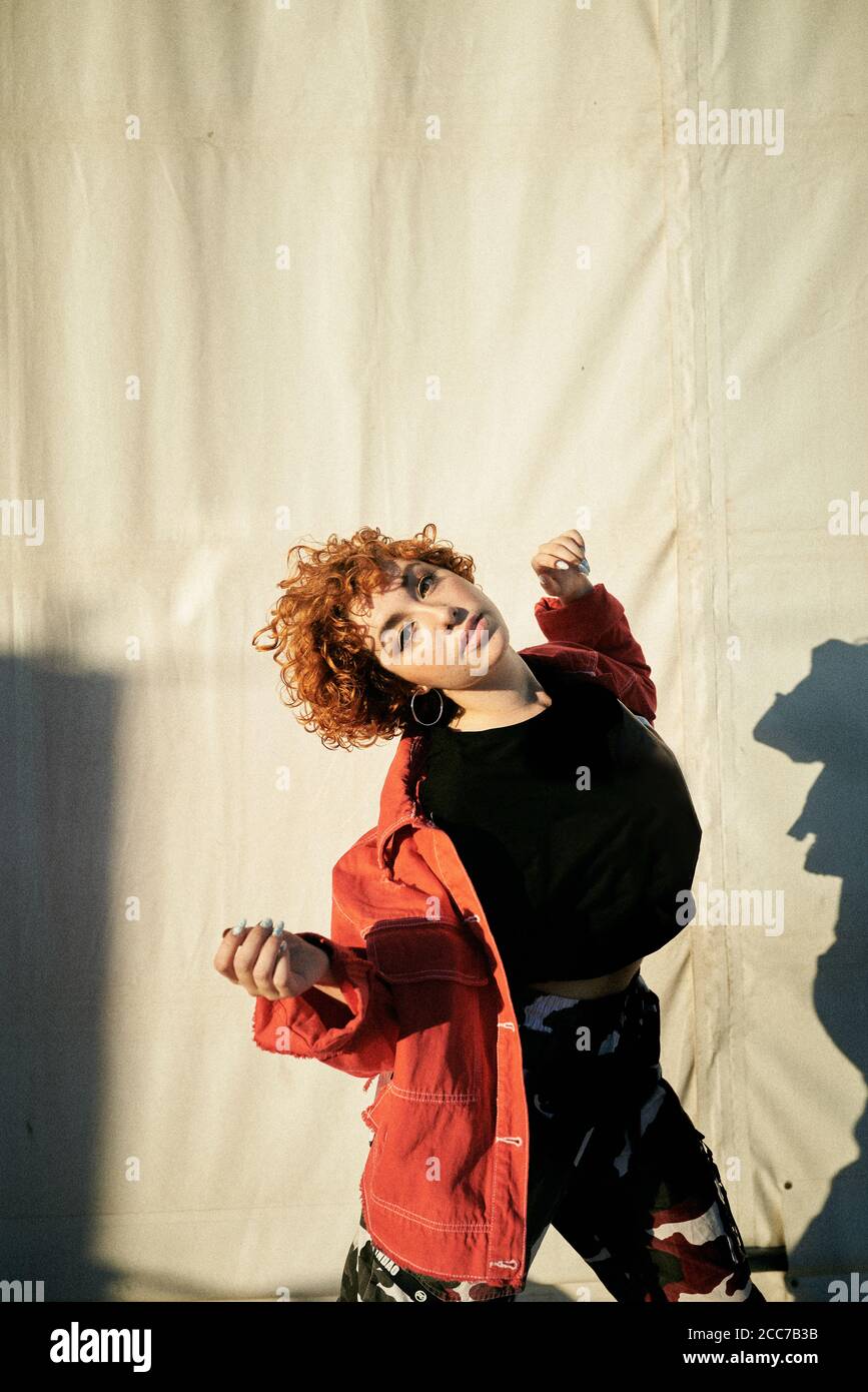 Alternative and modern redhead dancing with red jacket Stock Photo - Alamy