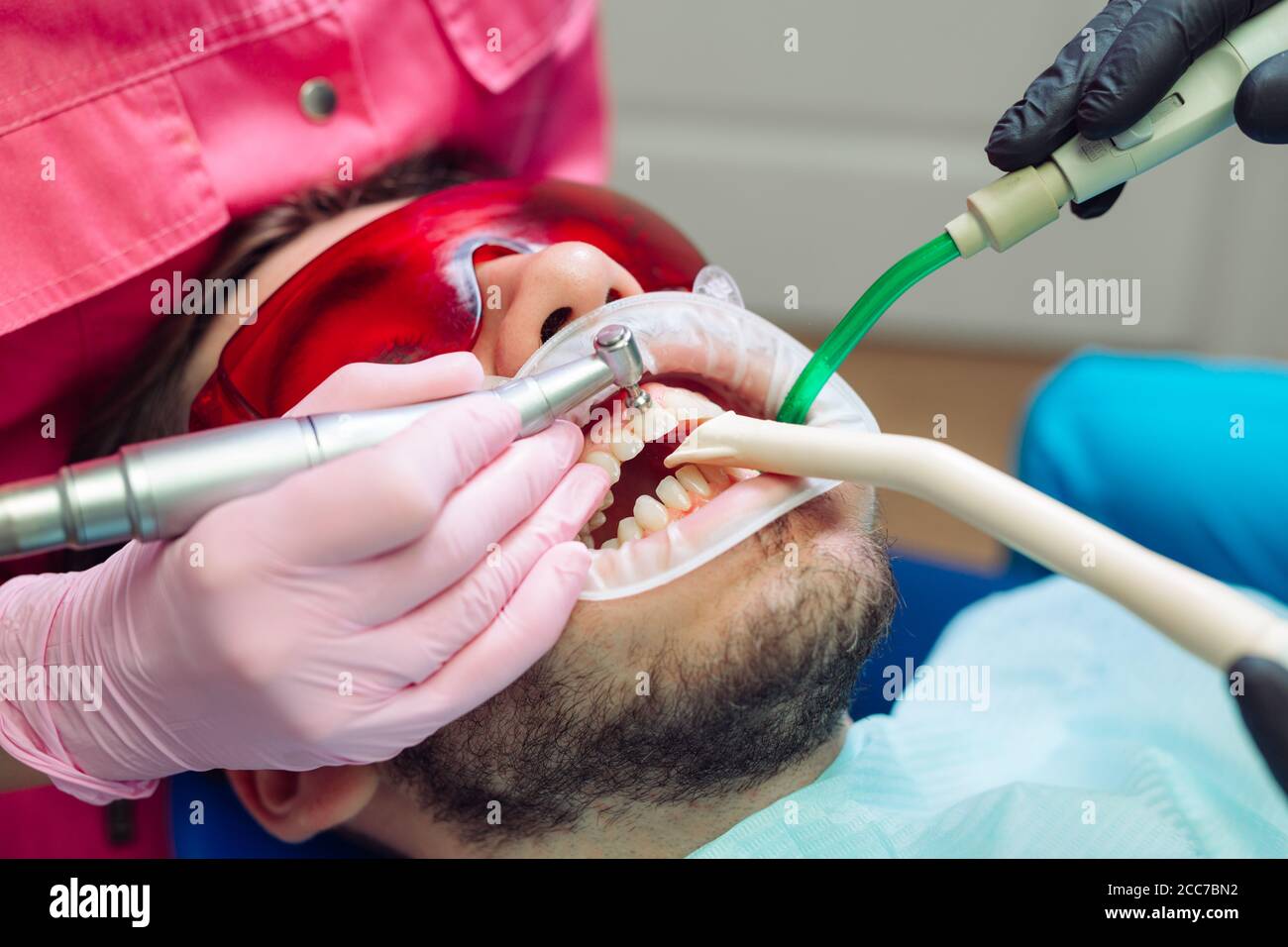 Professional teeth cleaning. Dentist cleans the teeth of a male patient ...