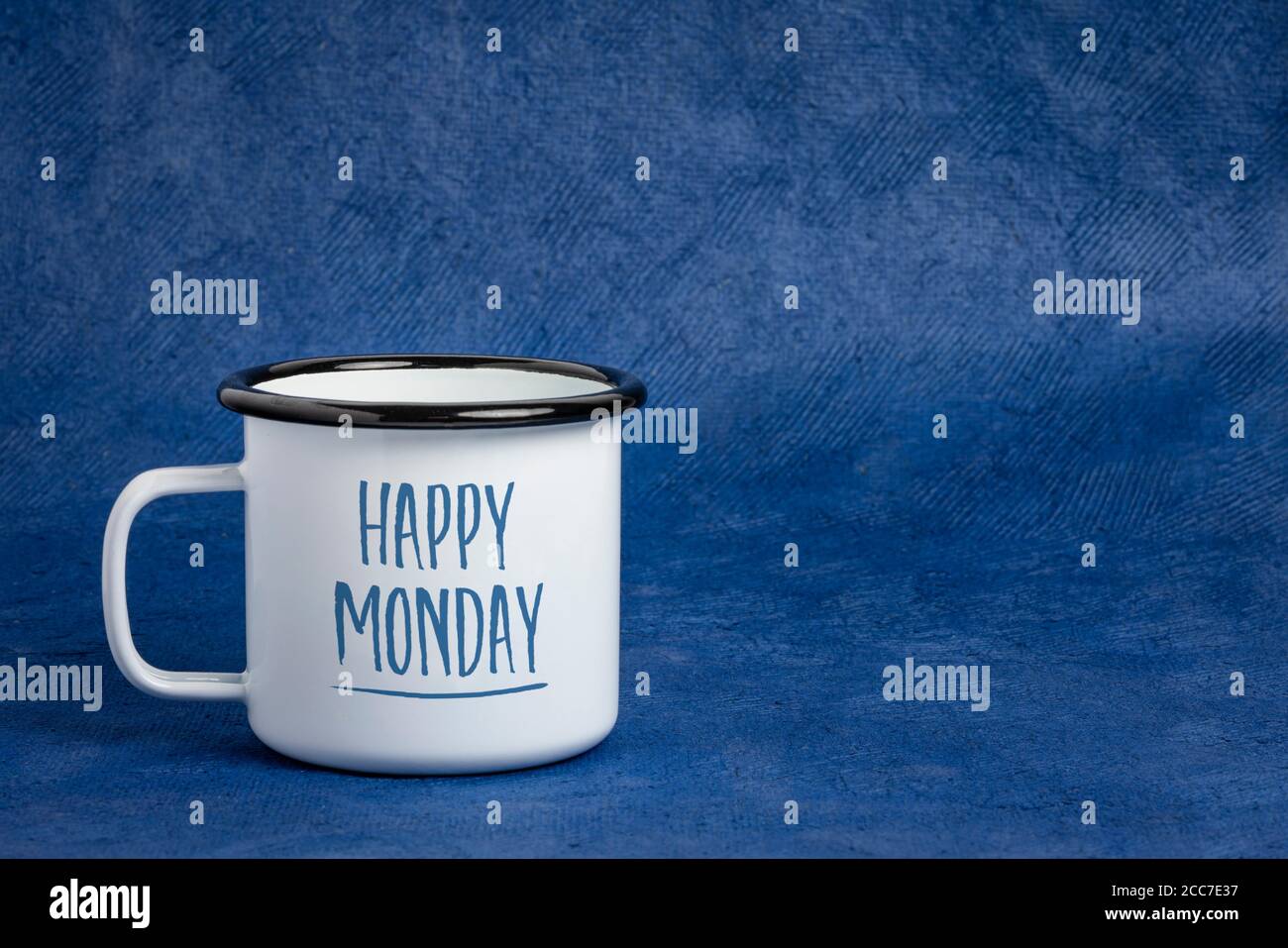 Happy Monday - white metal enamel cup of tea on a blue textured paper ...