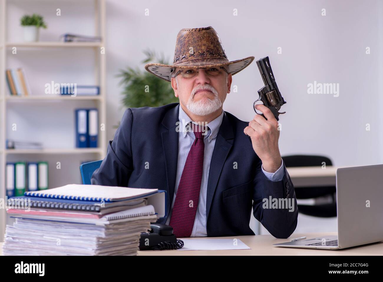 Funny old boss in cowboy hat in office Stock Photo - Alamy