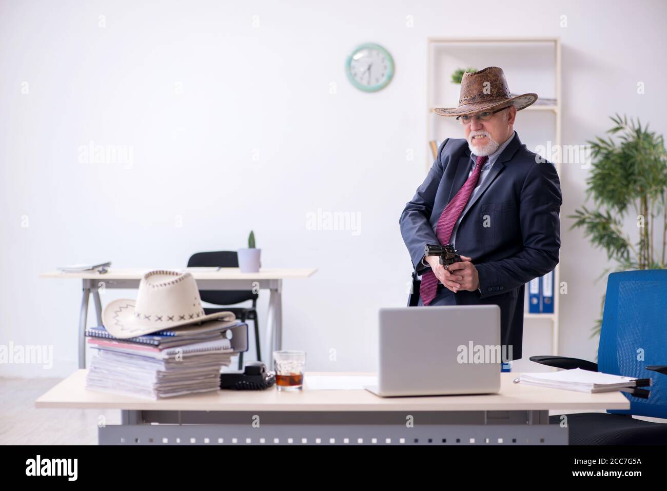 Funny old boss in cowboy hat in office Stock Photo - Alamy