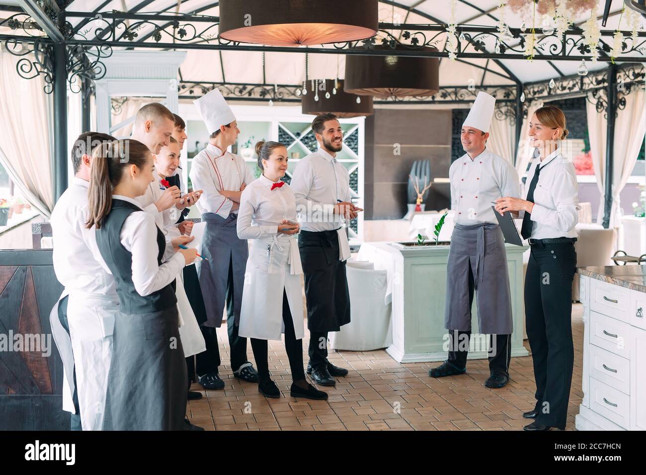 Restaurant manager and his staff in terrace. interacting to head chef ...