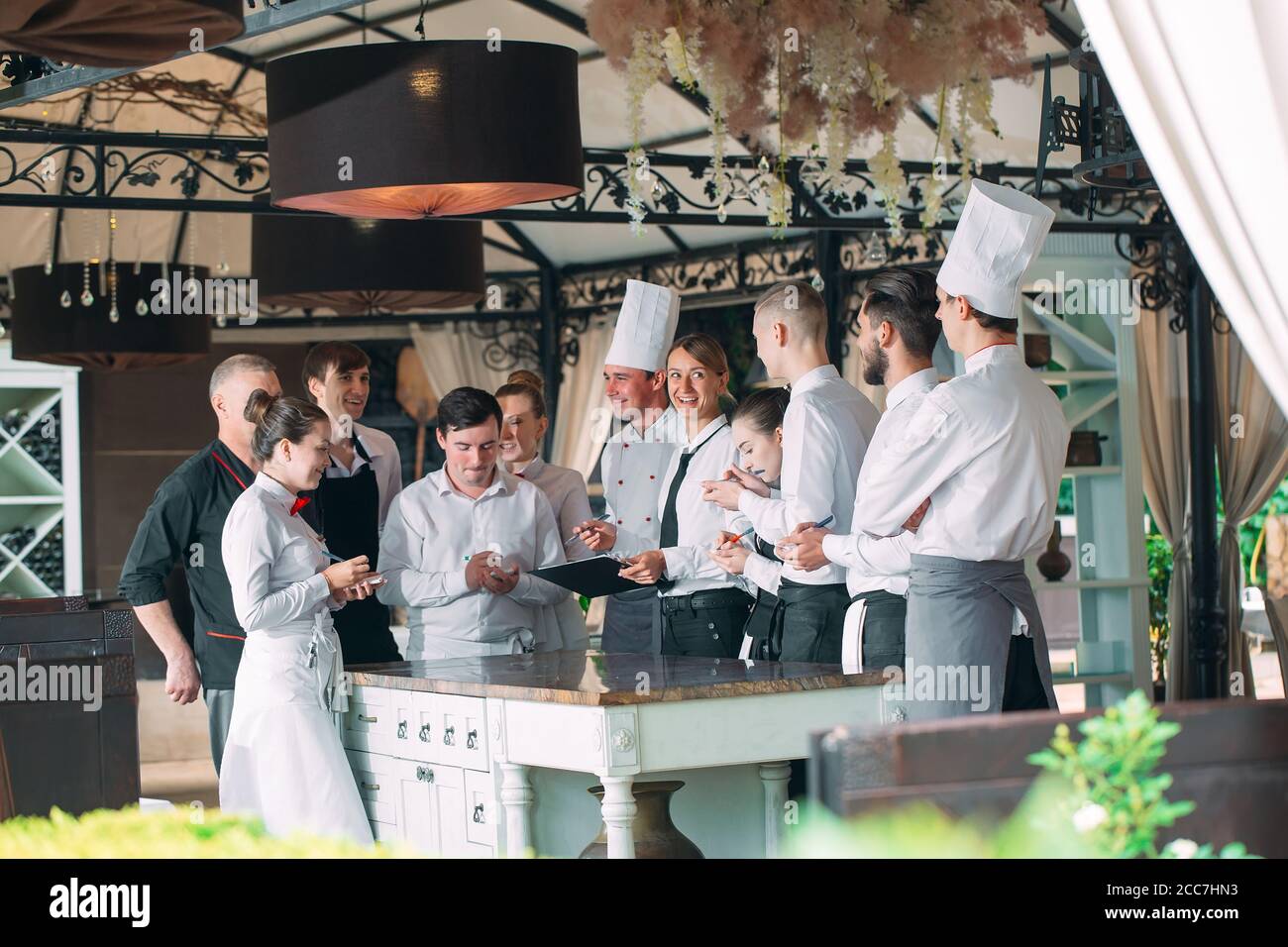 Restaurant manager and his staff in terrace. interacting to head chef ...